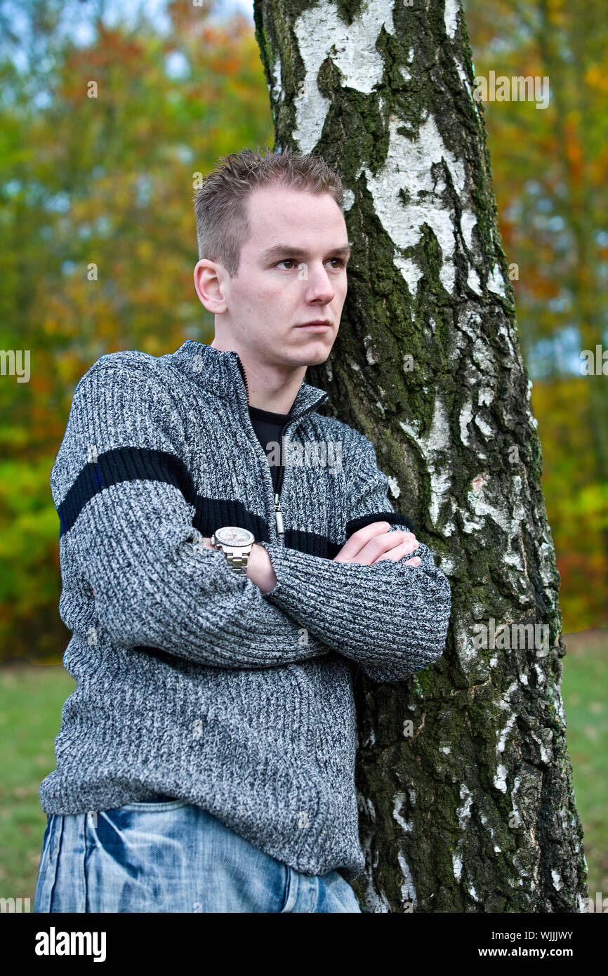 Boy is waiting befront of a tree Stock Photo - Alamy