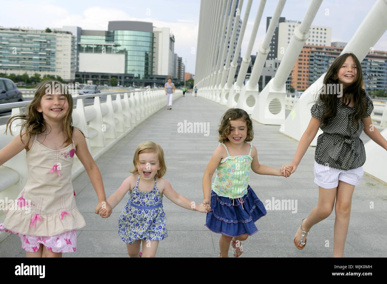 Four little girl group walking in the city bridge downtown buildings ...