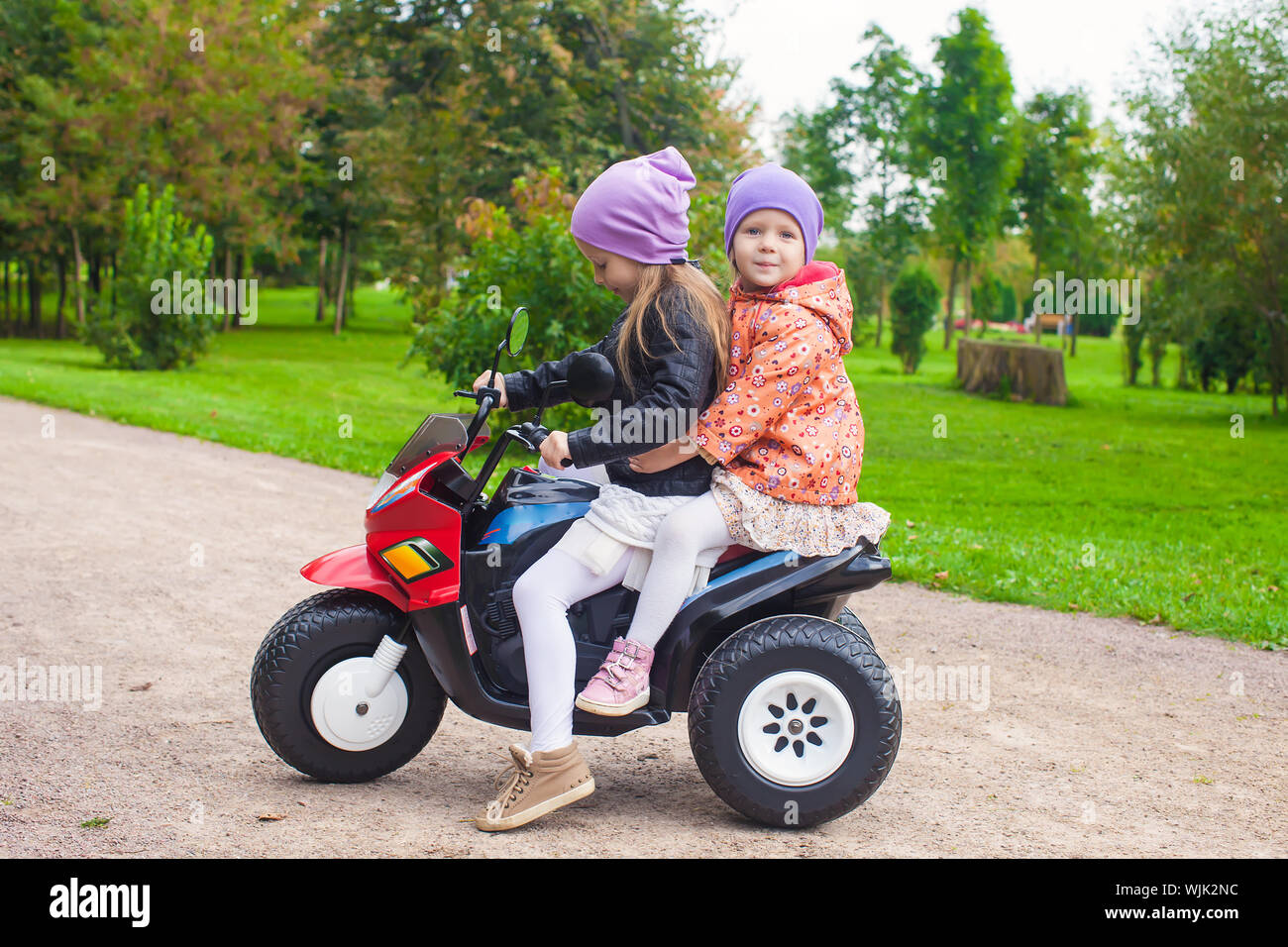Adorable little girls riding on kid's bike in the green park Stock ...