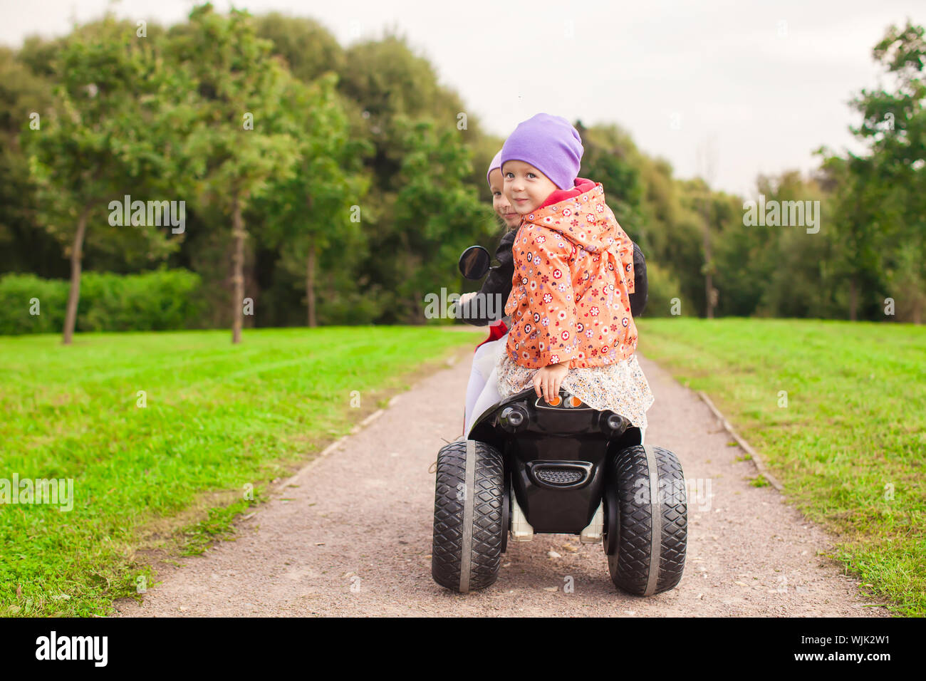 Happy little cute girls ride a motorbike outside Stock Photo - Alamy