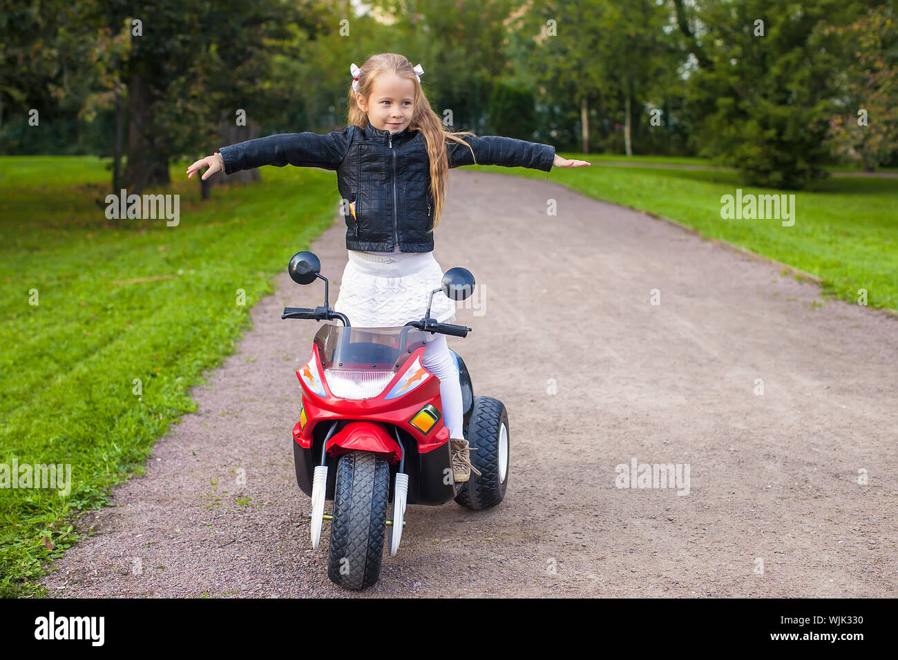 Adorable little girl having fun on her toy motorcycle Stock Photo - Alamy