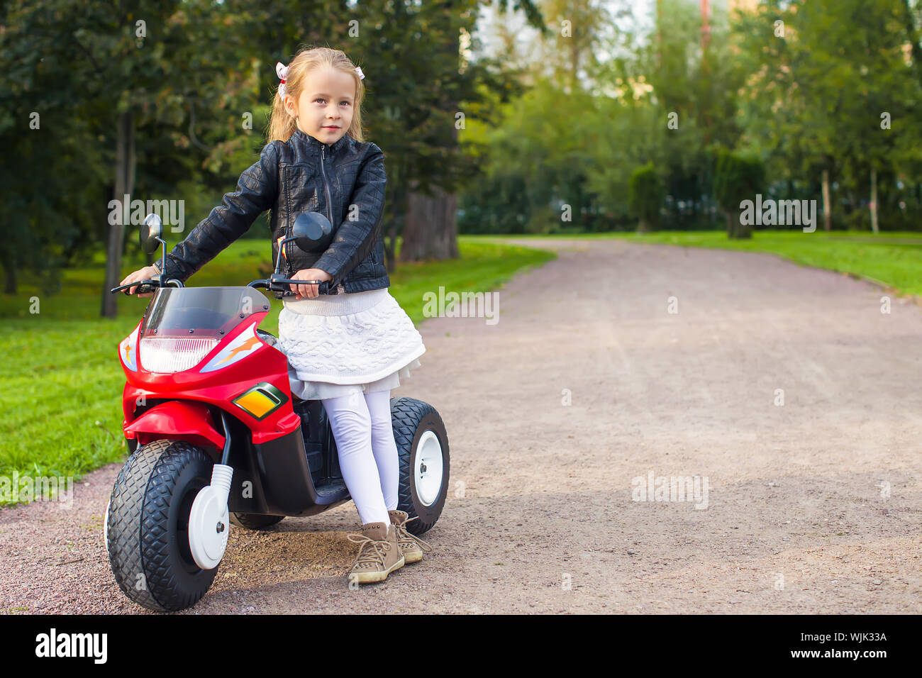 Beautiful little girl having fun on her toy motorcycle outdoors Stock ...