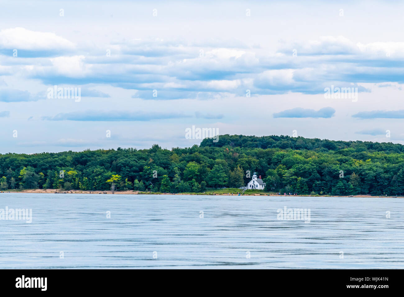 People walk on the beach in front of the Old Mission Point Lighthouse ...