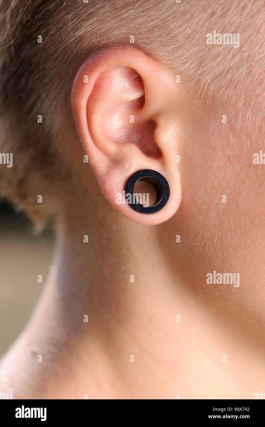 The big aperture in an ear at the teenager Stock Photo - Alamy
