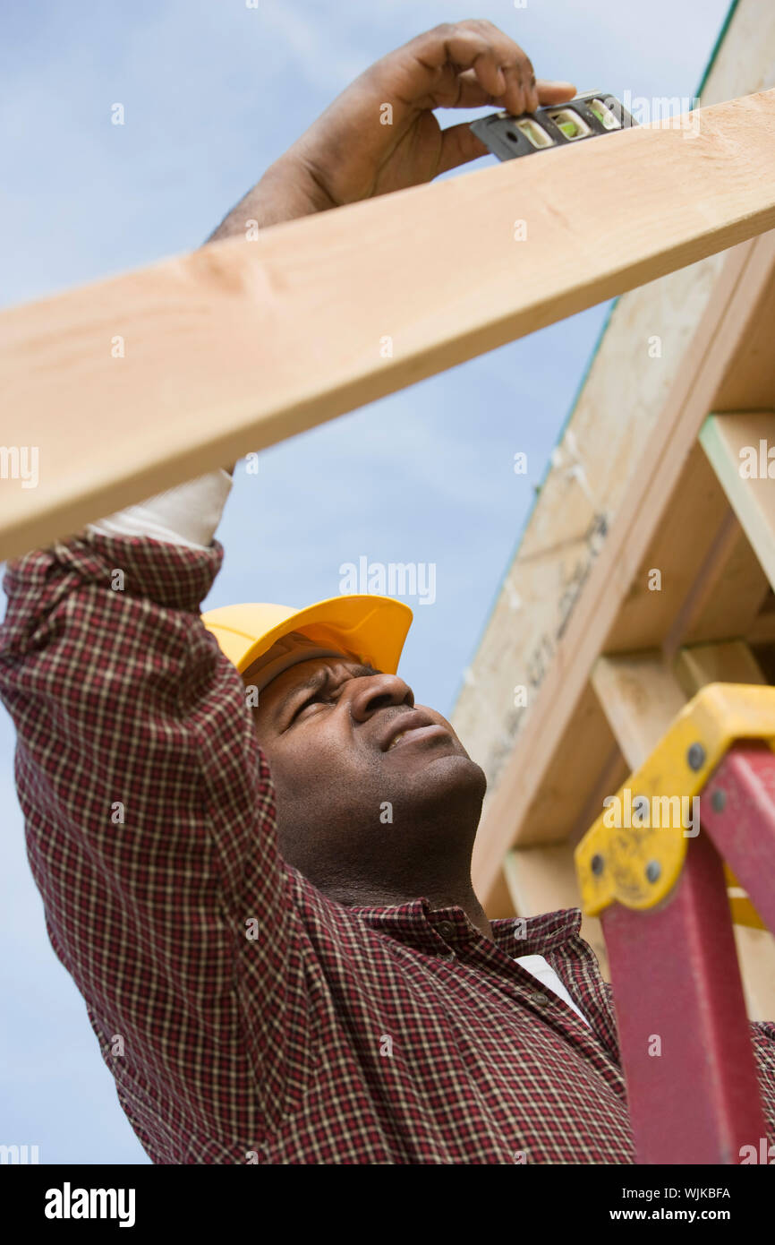 Construction worker using spirit level on building Stock Photo - Alamy