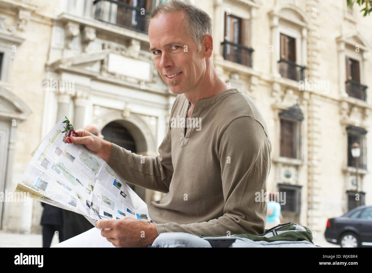 Portrait of happy middle aged man holding map in front of building ...