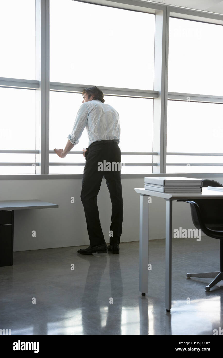 Rear view of a businessman looking out of office window Stock Photo - Alamy