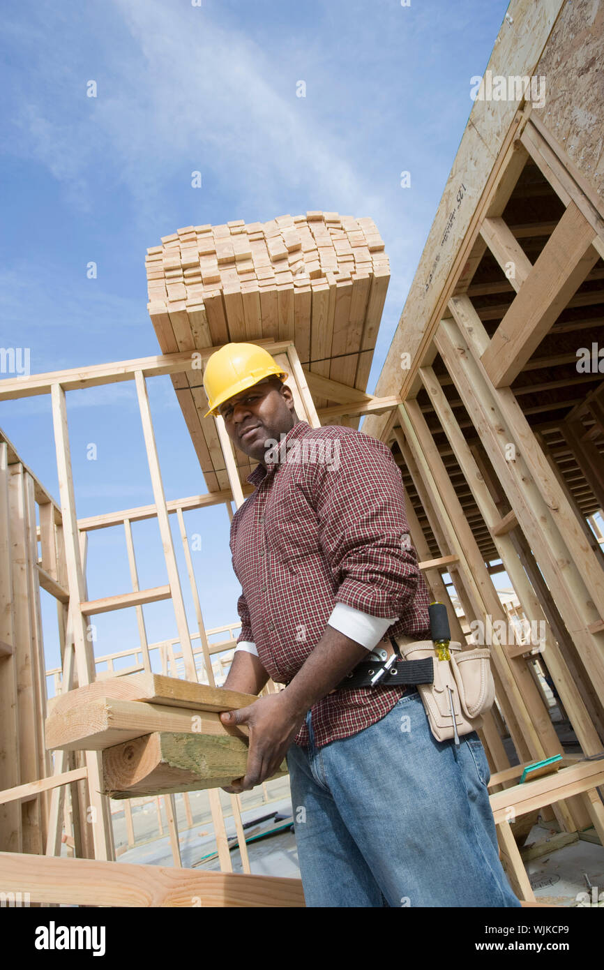 Construction worker carrying wooden plank Stock Photo - Alamy