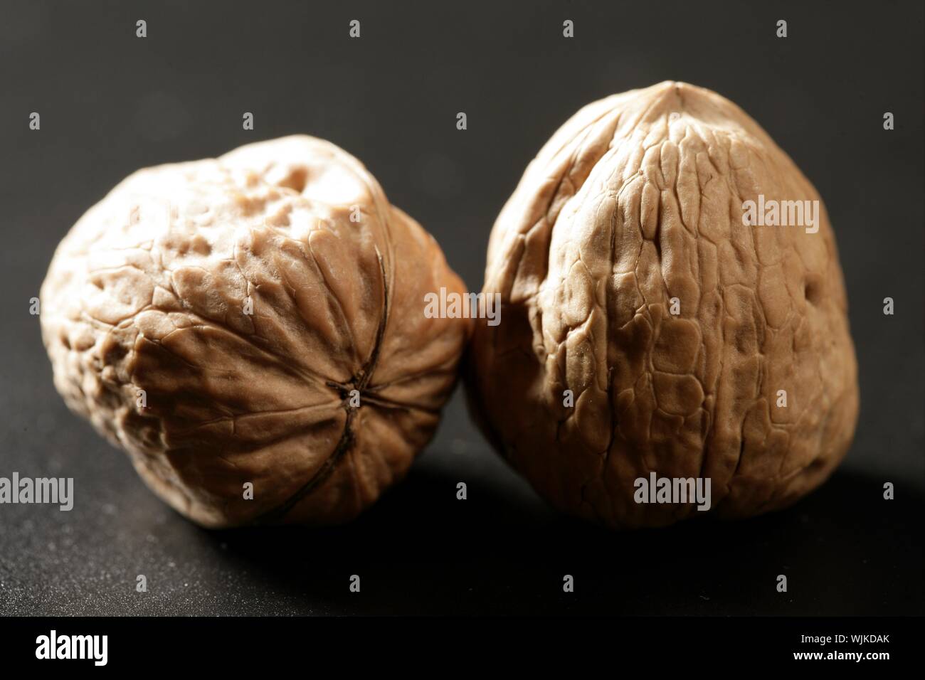 Two walnuts with shells over black background Stock Photo - Alamy