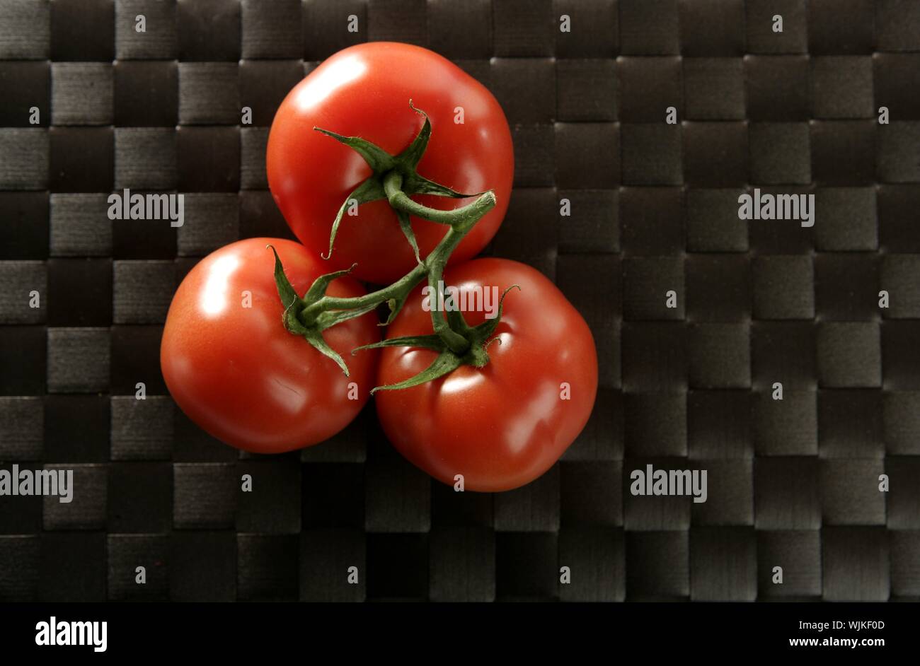 Three red tomatoes in the same one branch over a green plate Stock ...