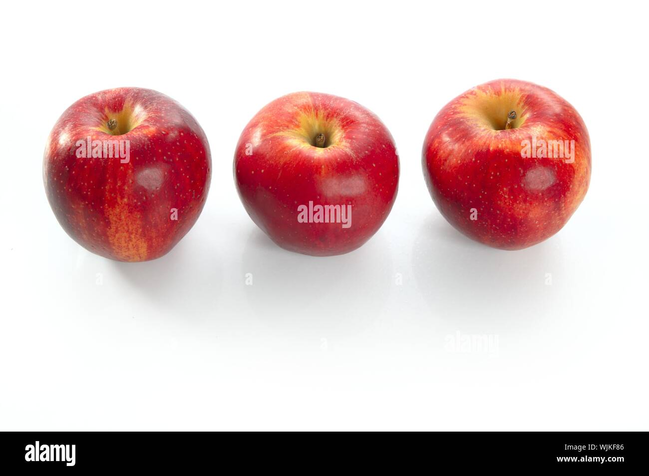 Three red apples in a row over white background Stock Photo - Alamy