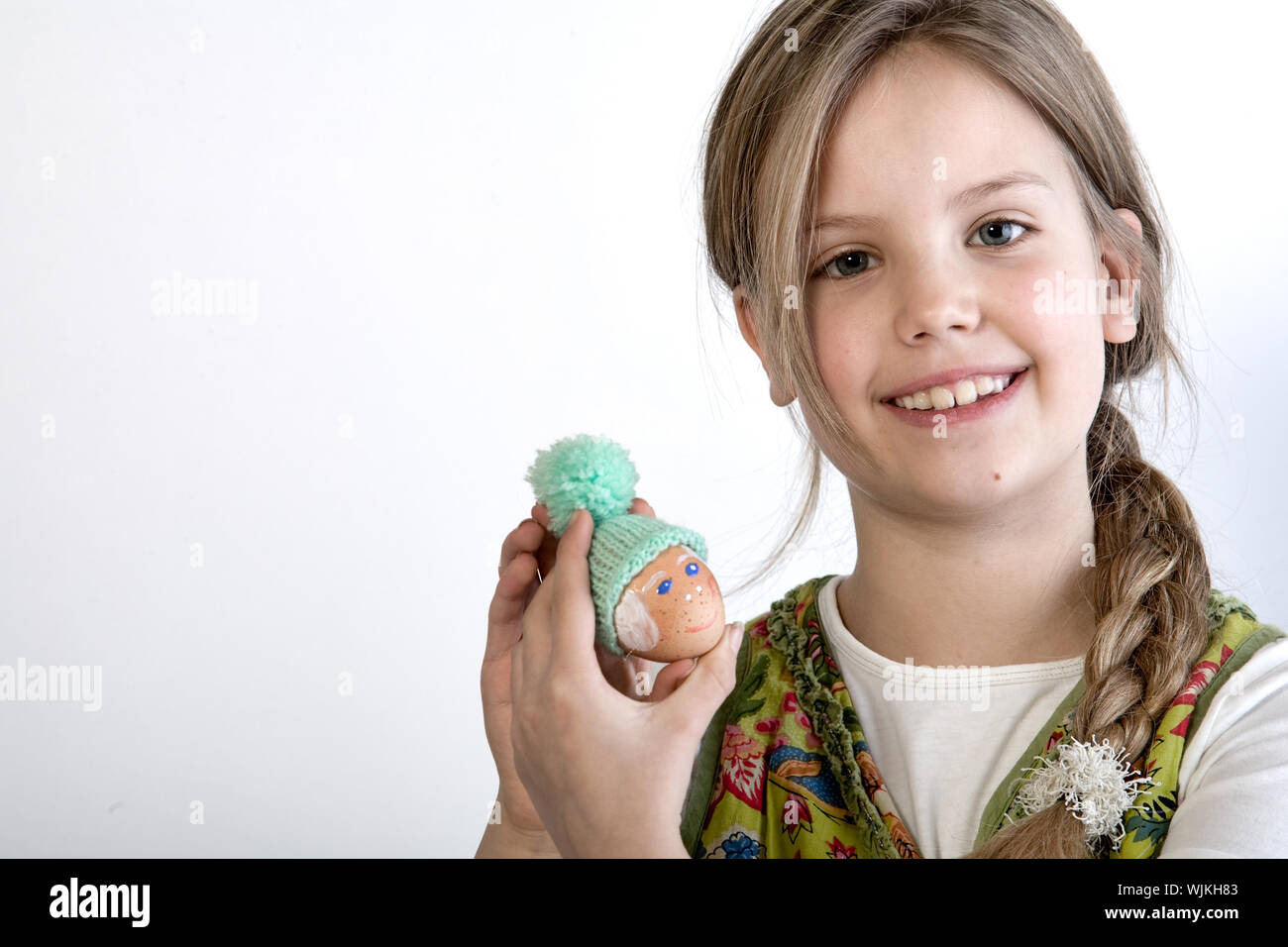 Studio portrait of a young blond girl who is showing her painted easter ...