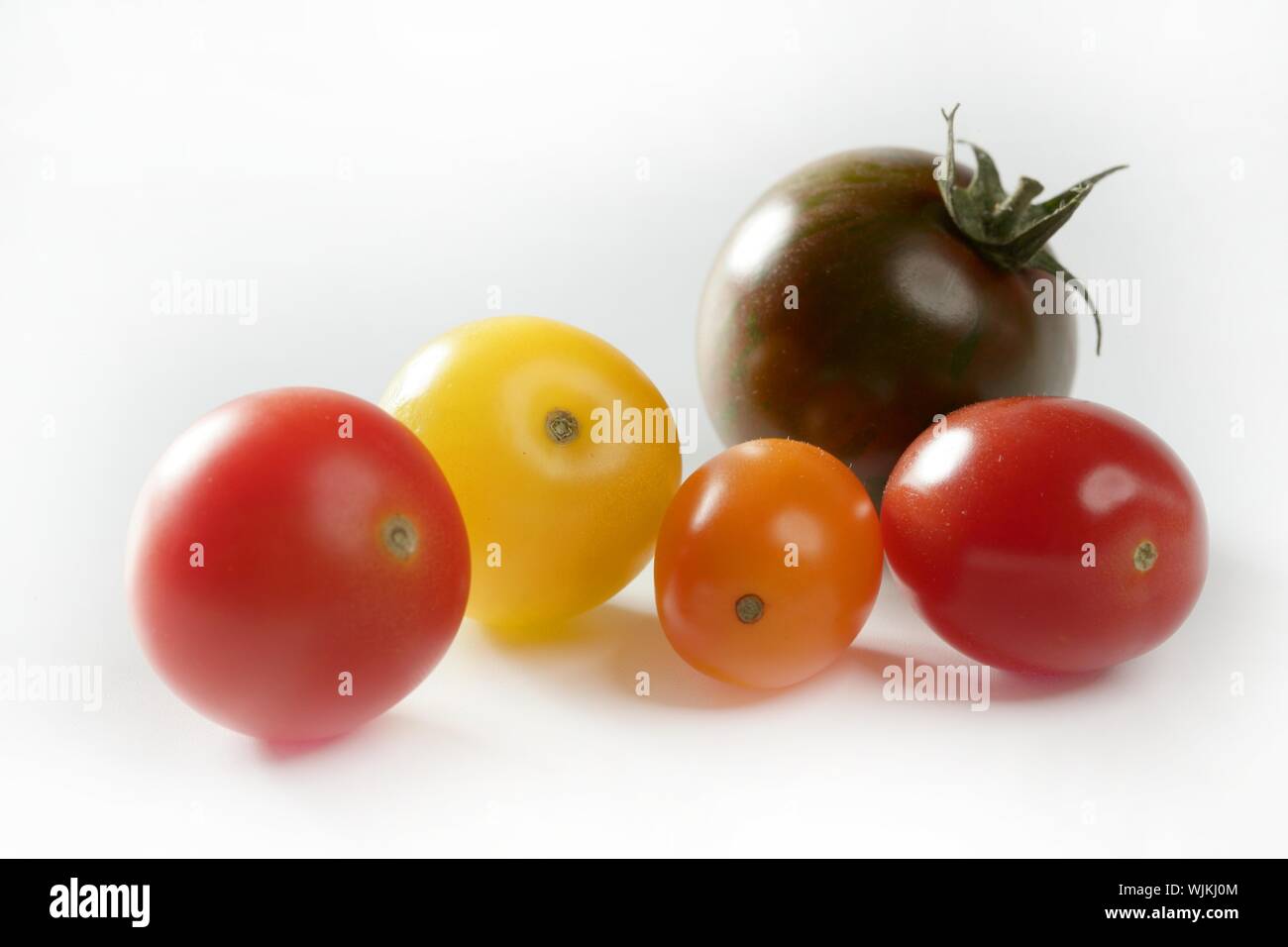 Little cherry varied multi color tomatoes, at studio, white background ...
