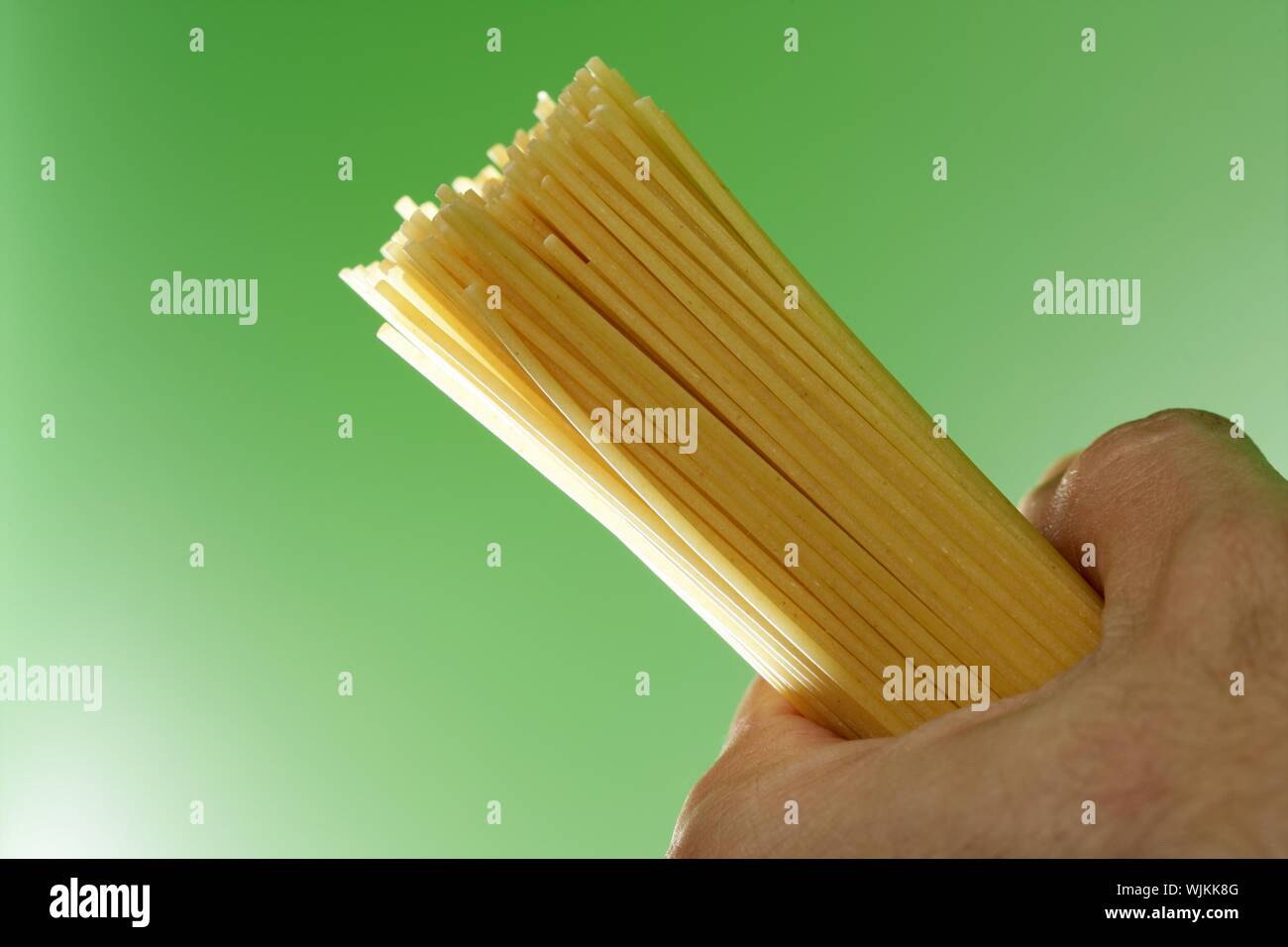spaghetti in humand hand on green background at studio Stock Photo - Alamy