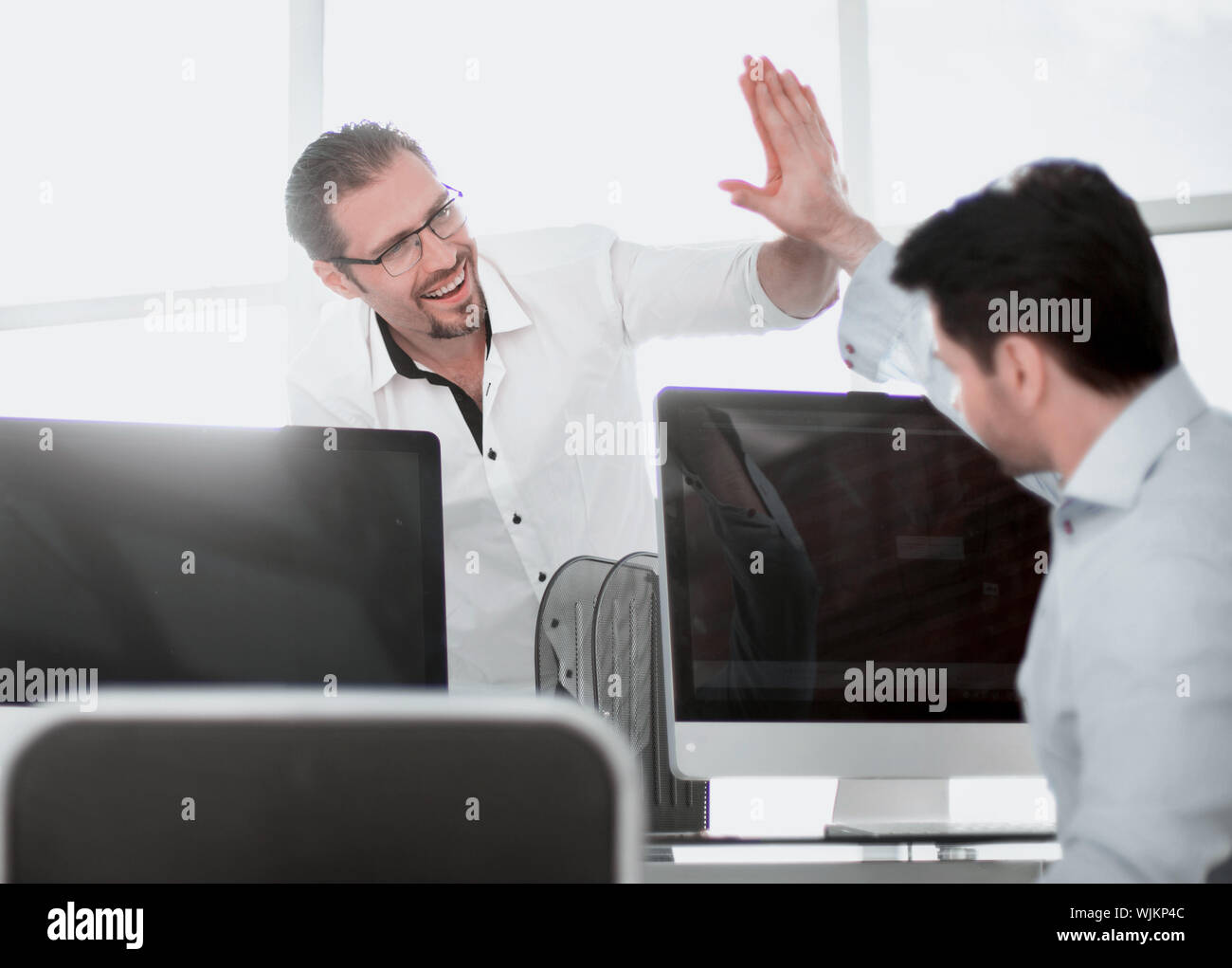 employees give each other a high five over the computer Desk Stock ...