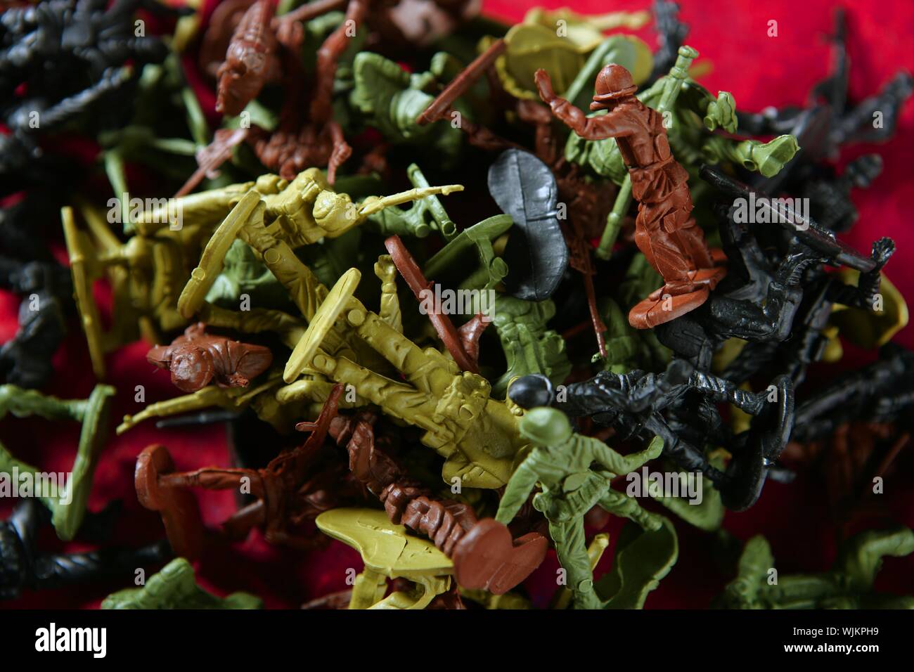 Metaphor of dead plastic toy war soldiers on a red bloody background ...