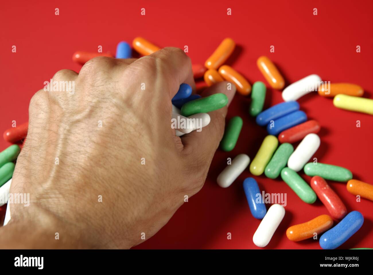 Human hand holding colorful candy sweets over red background Stock ...
