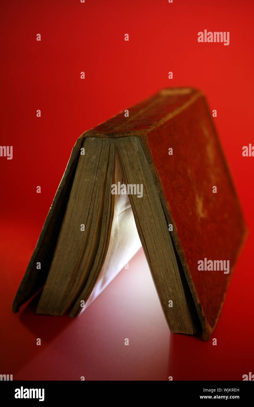 Old aged book close up, light glowing inside, over red background Stock ...