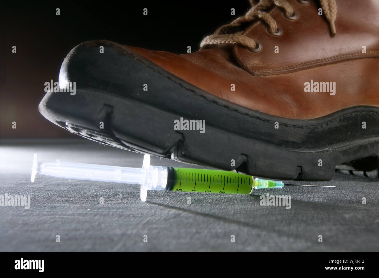 Boot treading a green liquid syringe, leaving drug addiction metaphor ...