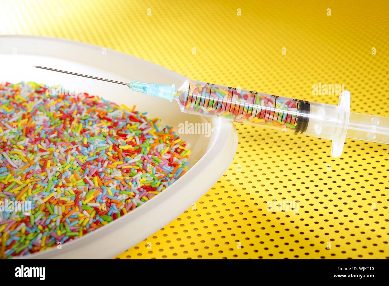 Little colorful candy syringe over yellow background, health metaphor ...