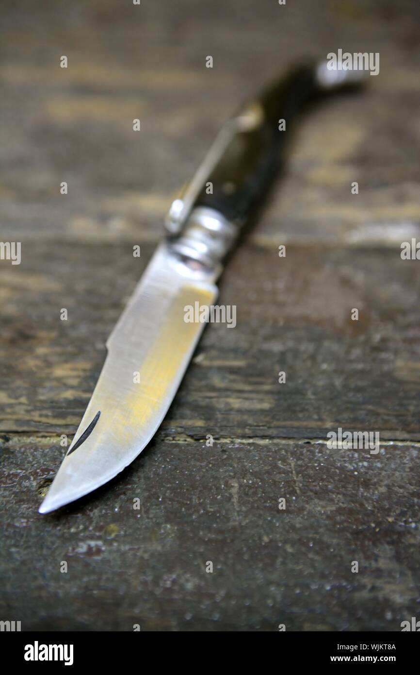 Open knife hand weapon over an aged wooden table Stock Photo - Alamy