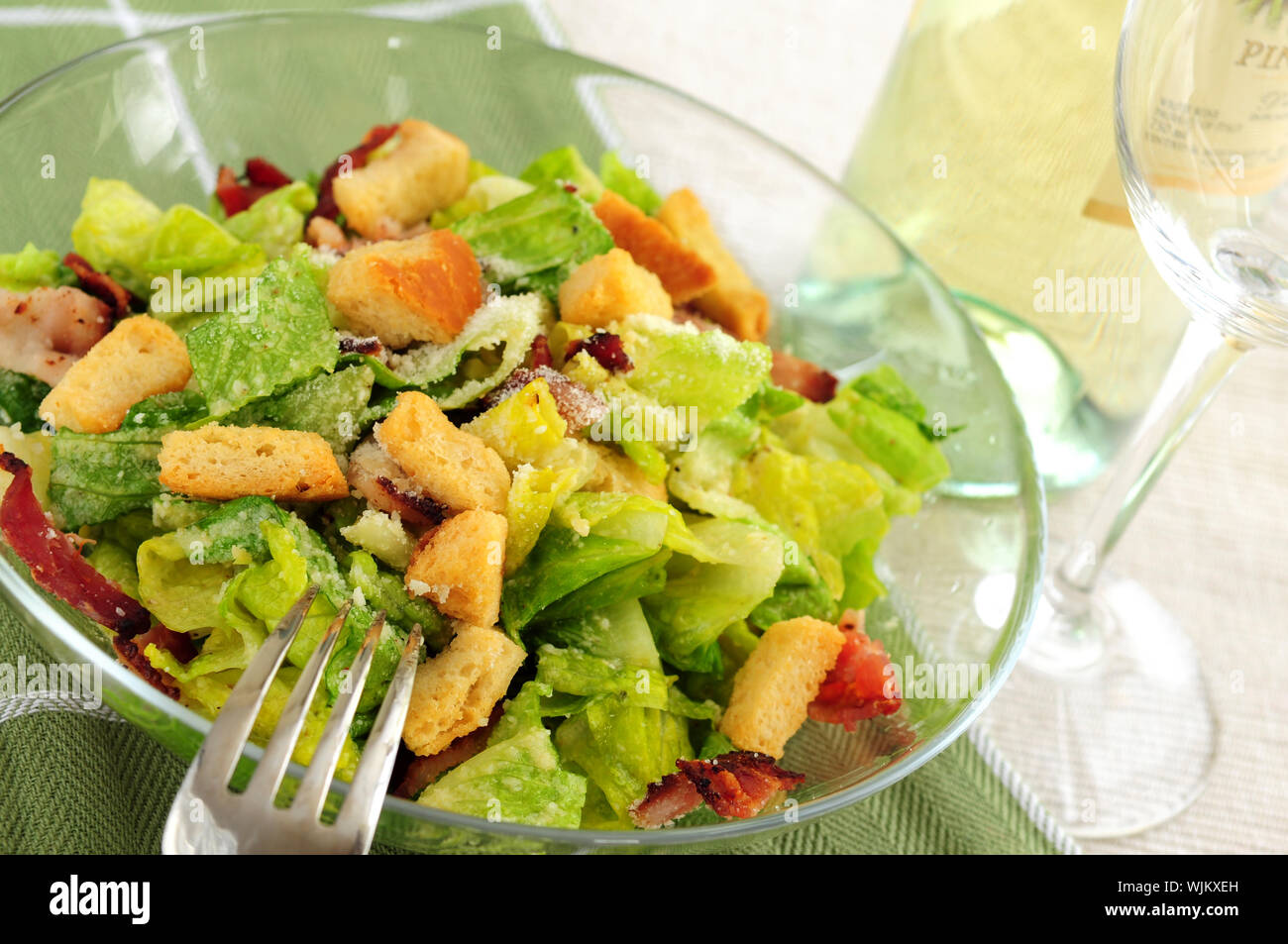 Caesar salad served in a glass bowl and white wine Stock Photo - Alamy