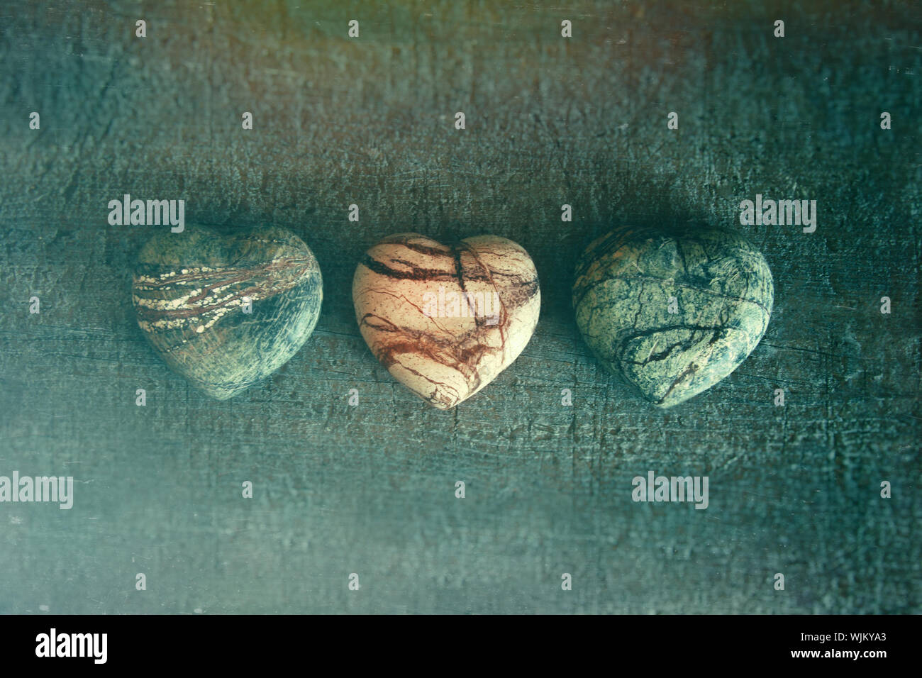 Three stone hearts on wood background Stock Photo - Alamy