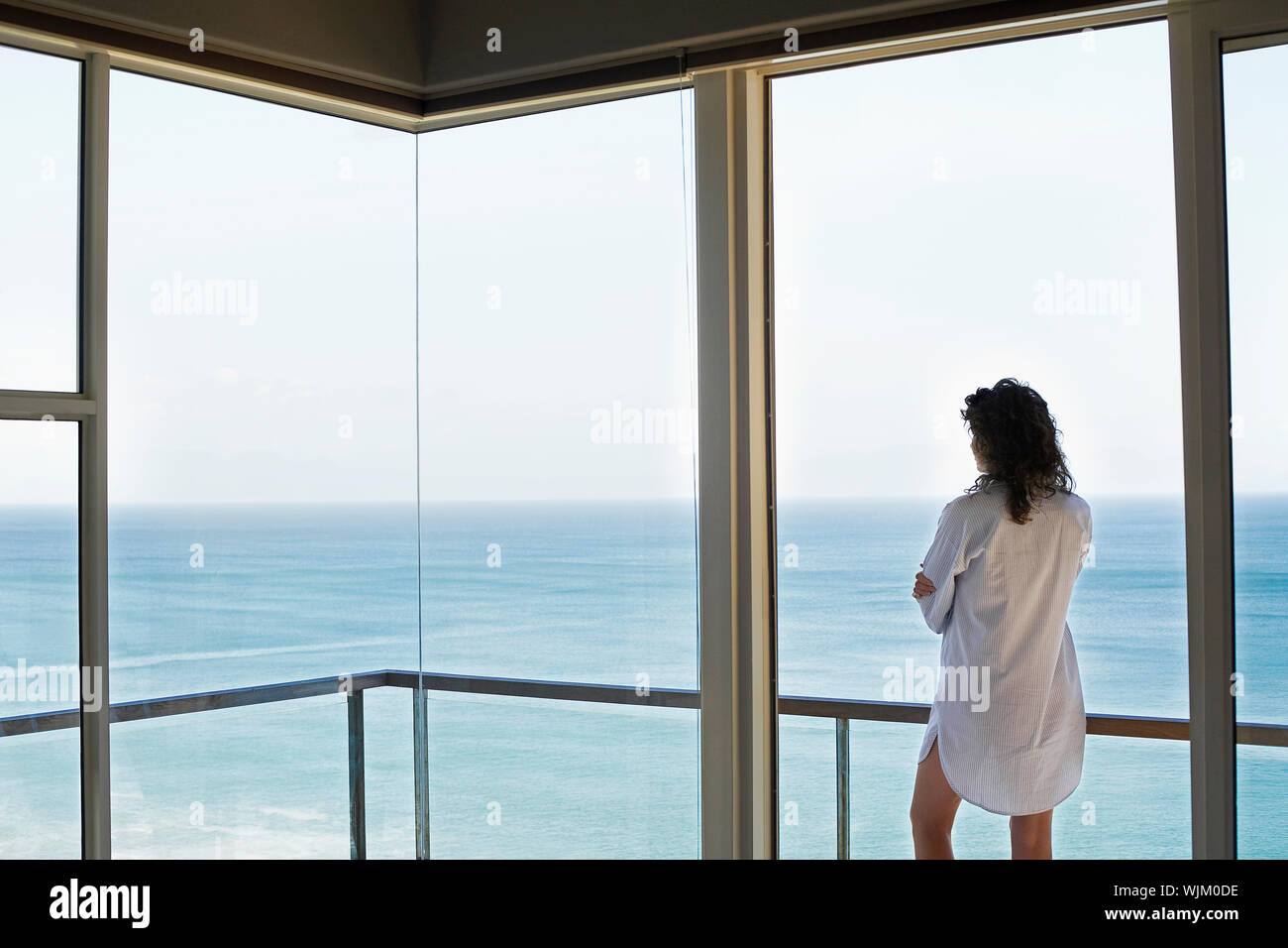 Woman Looking Through Window at Ocean Stock Photo - Alamy