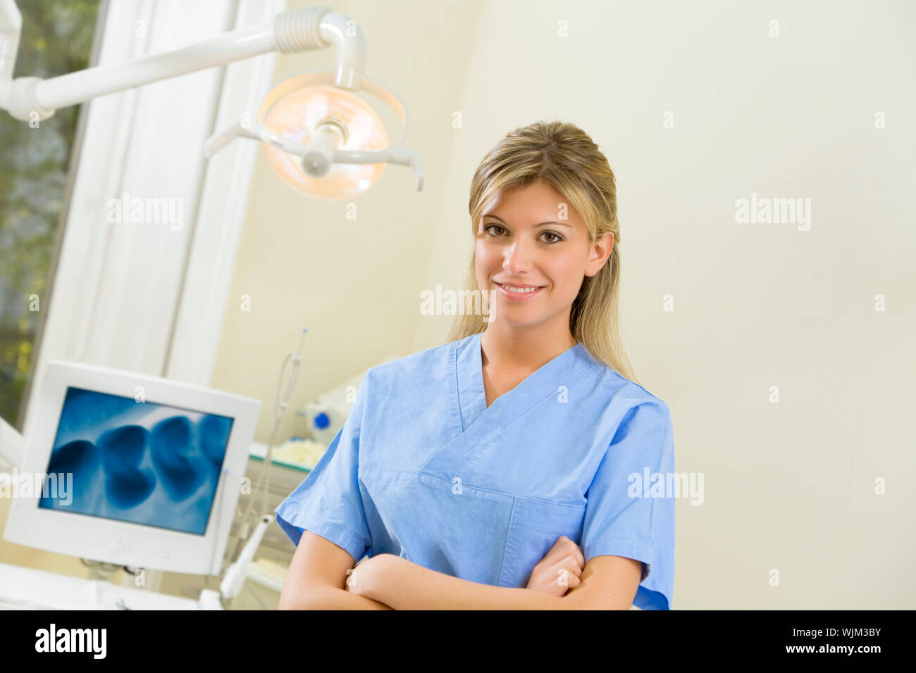 young dental assistant smiling. X-ray image on the computer monitor in ...