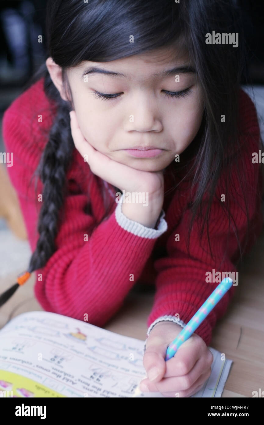 Little girl frowning while doing homework Stock Photo - Alamy