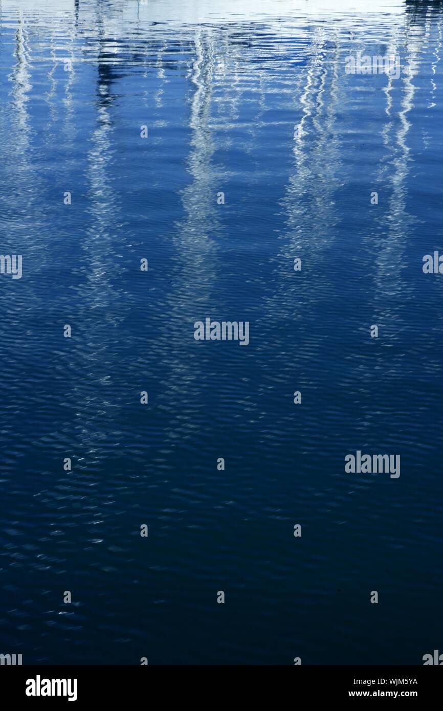 Sailboat blurred mast reflexion on the marina blue sea water Stock ...