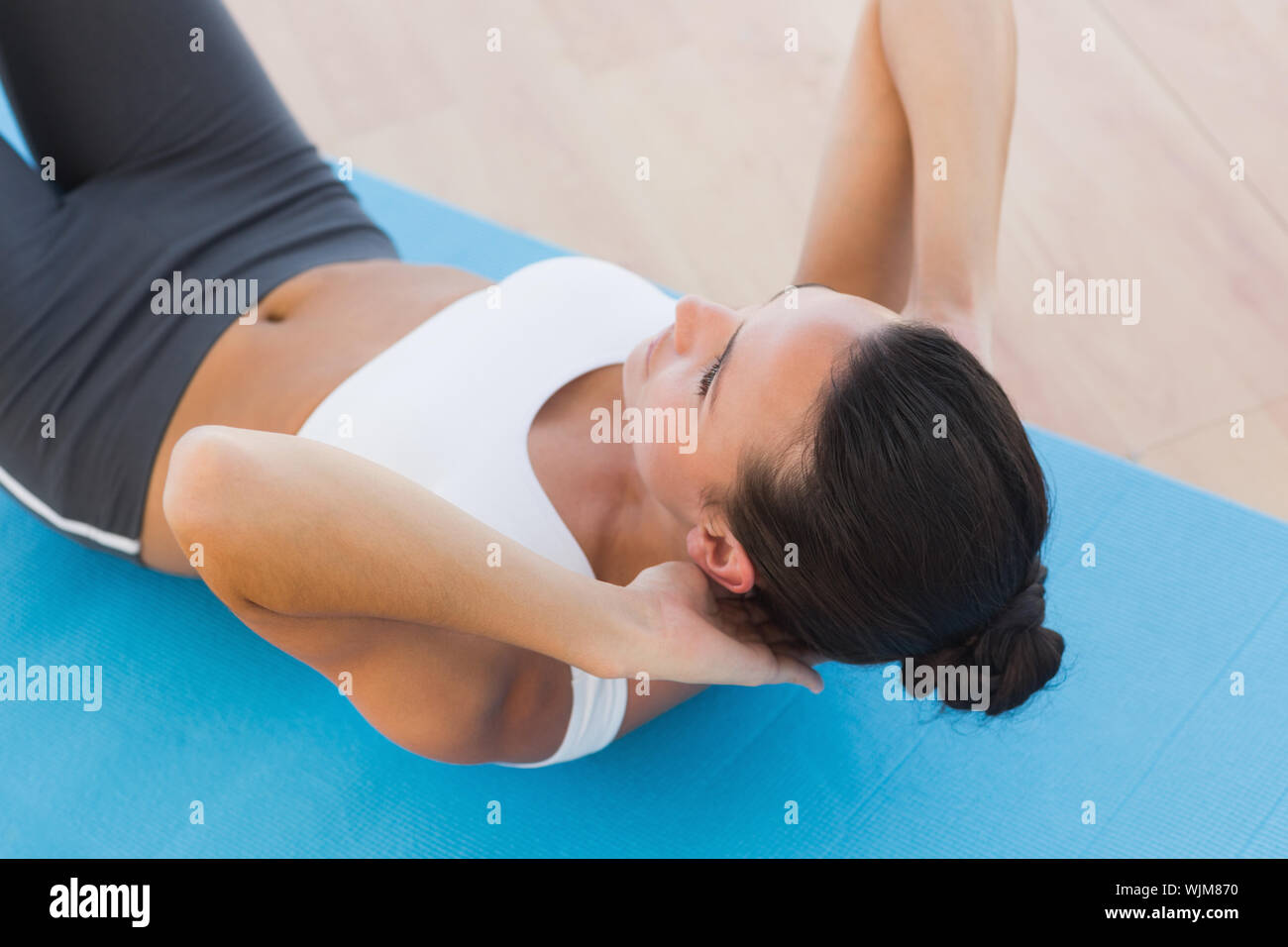 Determined young woman doing abdominal crunches on exercise mat at a ...