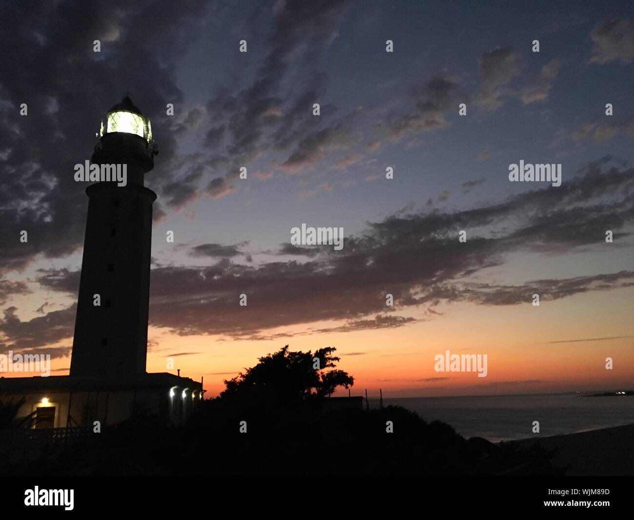 Trafalgar lighthouse on the coast of Cadiz at sunset Stock Photo - Alamy