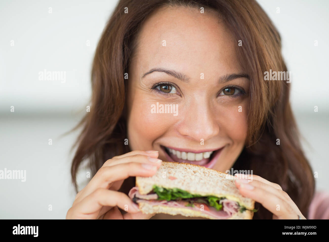 Closeup portrait of a beautiful smiling young woman eating sandwich ...
