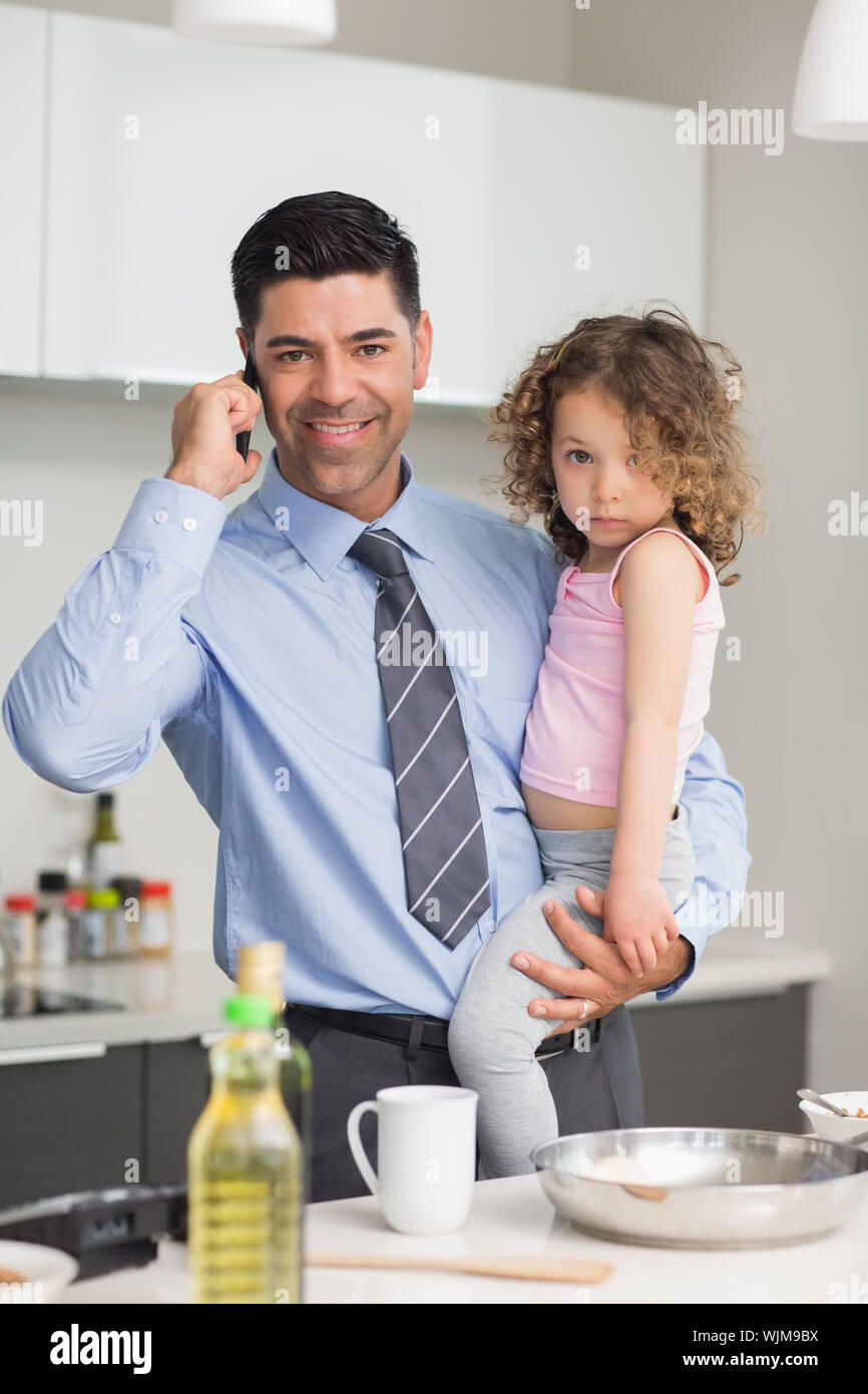Well dressed father carrying daughter while on call in the kitchen at ...