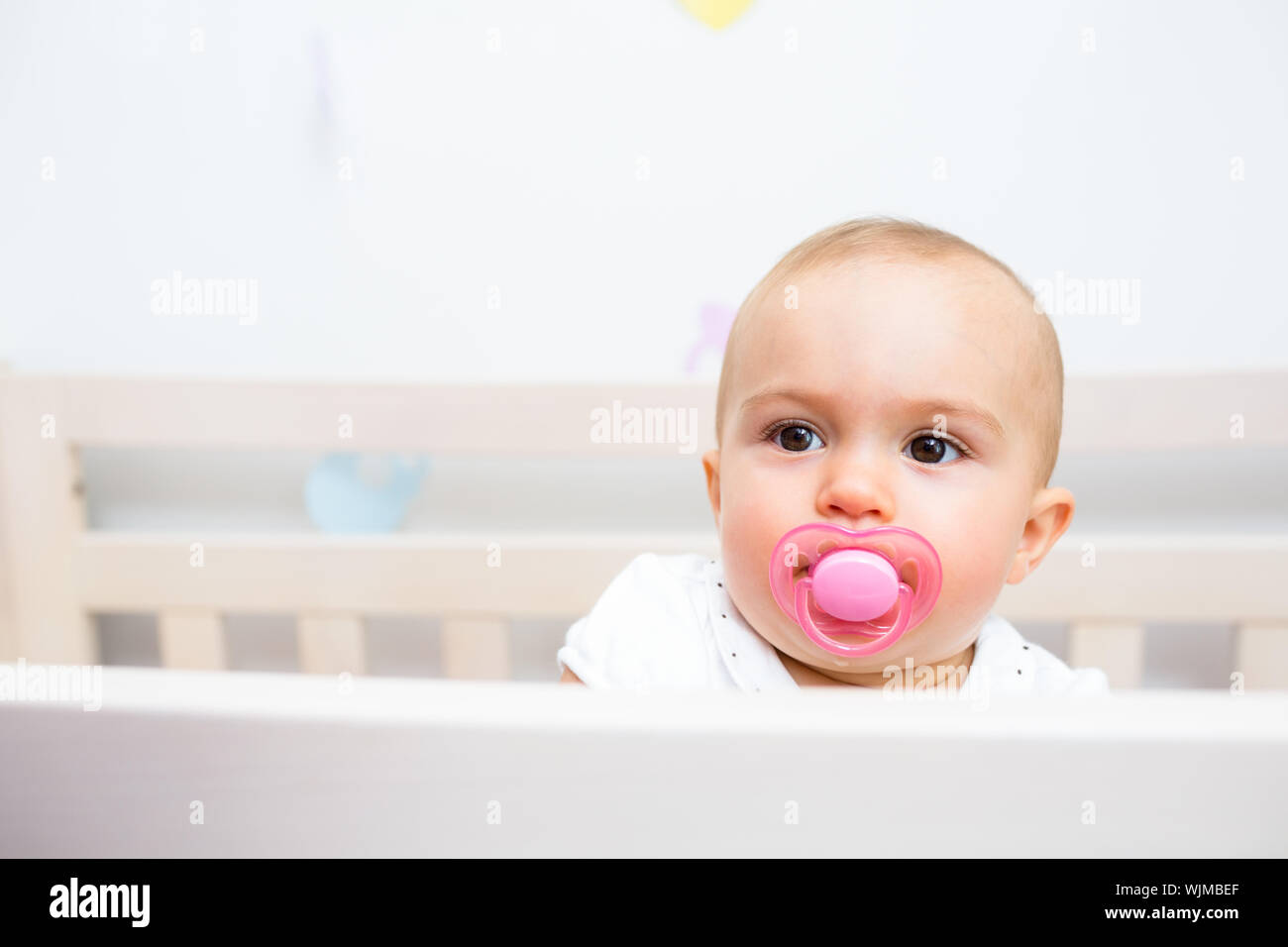 Closeup portrait of a cute baby with pacifier in mouth over blurred ...