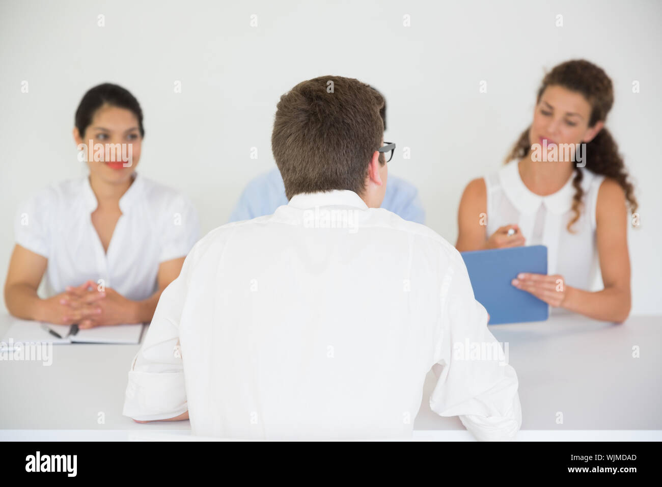 Panel of business people conducting job interview with male candidate ...