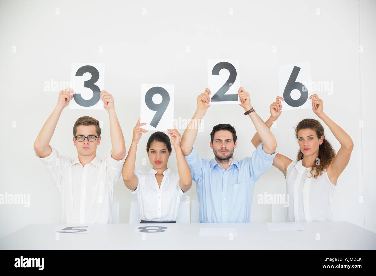 Portrait of business people holding score cards at desk in office Stock ...