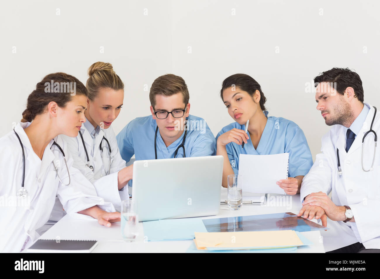 Concentrated doctors and nurses discussing over laptop in hospital ...