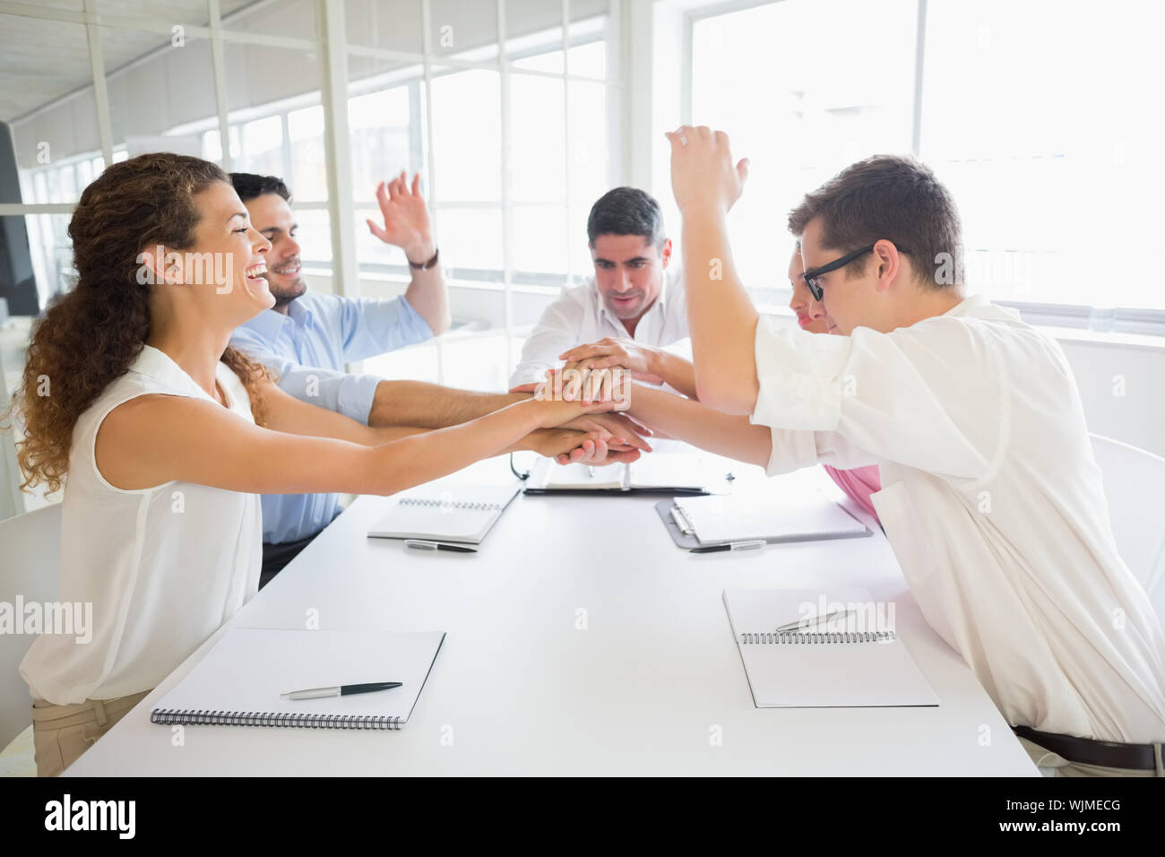 United business people stacking hands at conference table in office ...