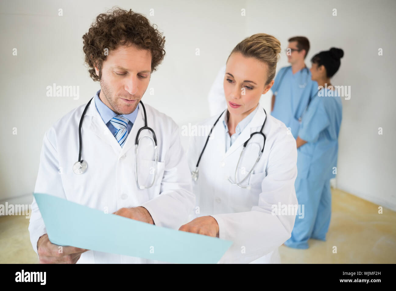 Concentrated doctors reading file in hospital Stock Photo - Alamy