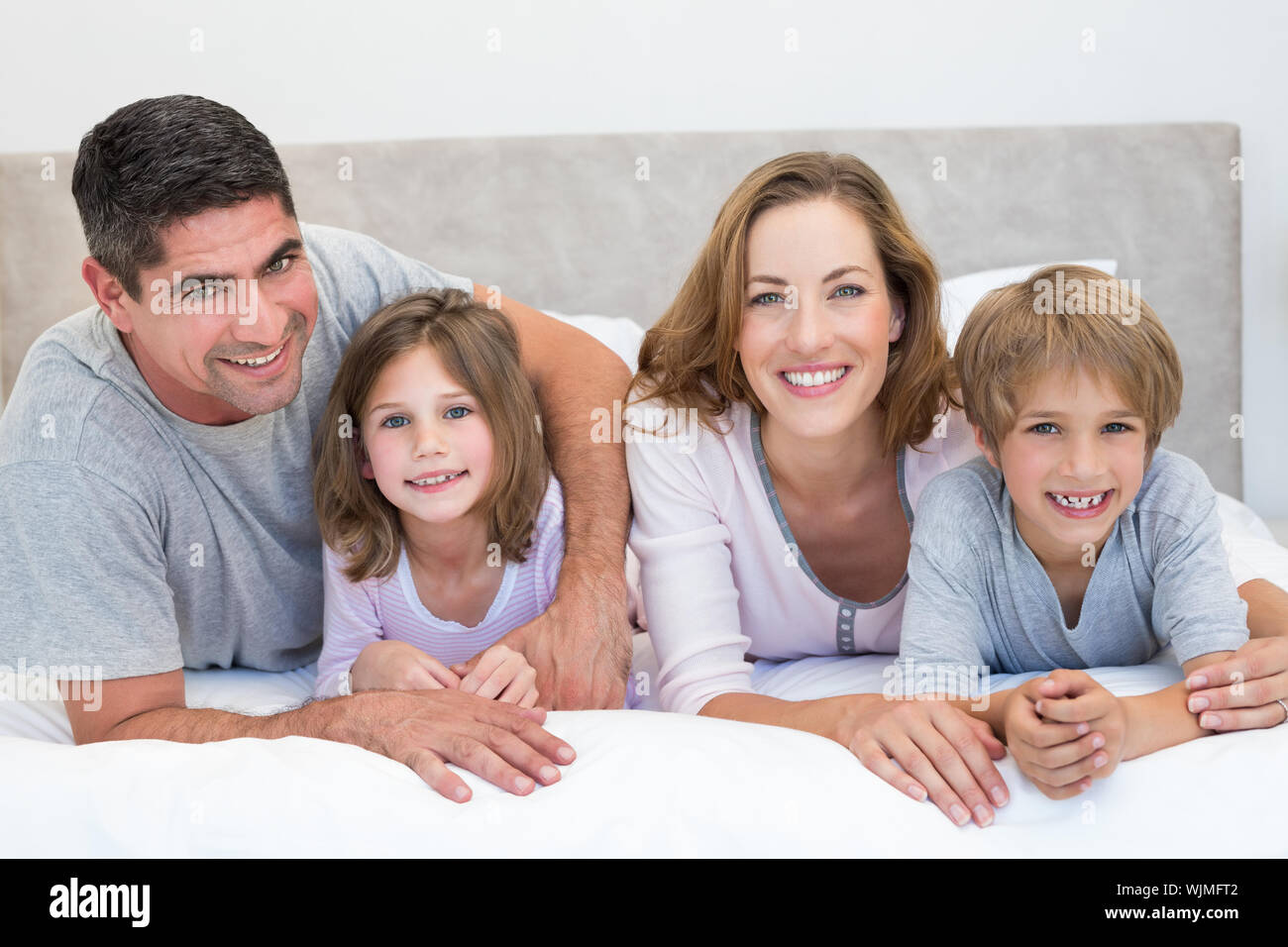 Portrait of smiling family lying side by side in bed Stock Photo - Alamy