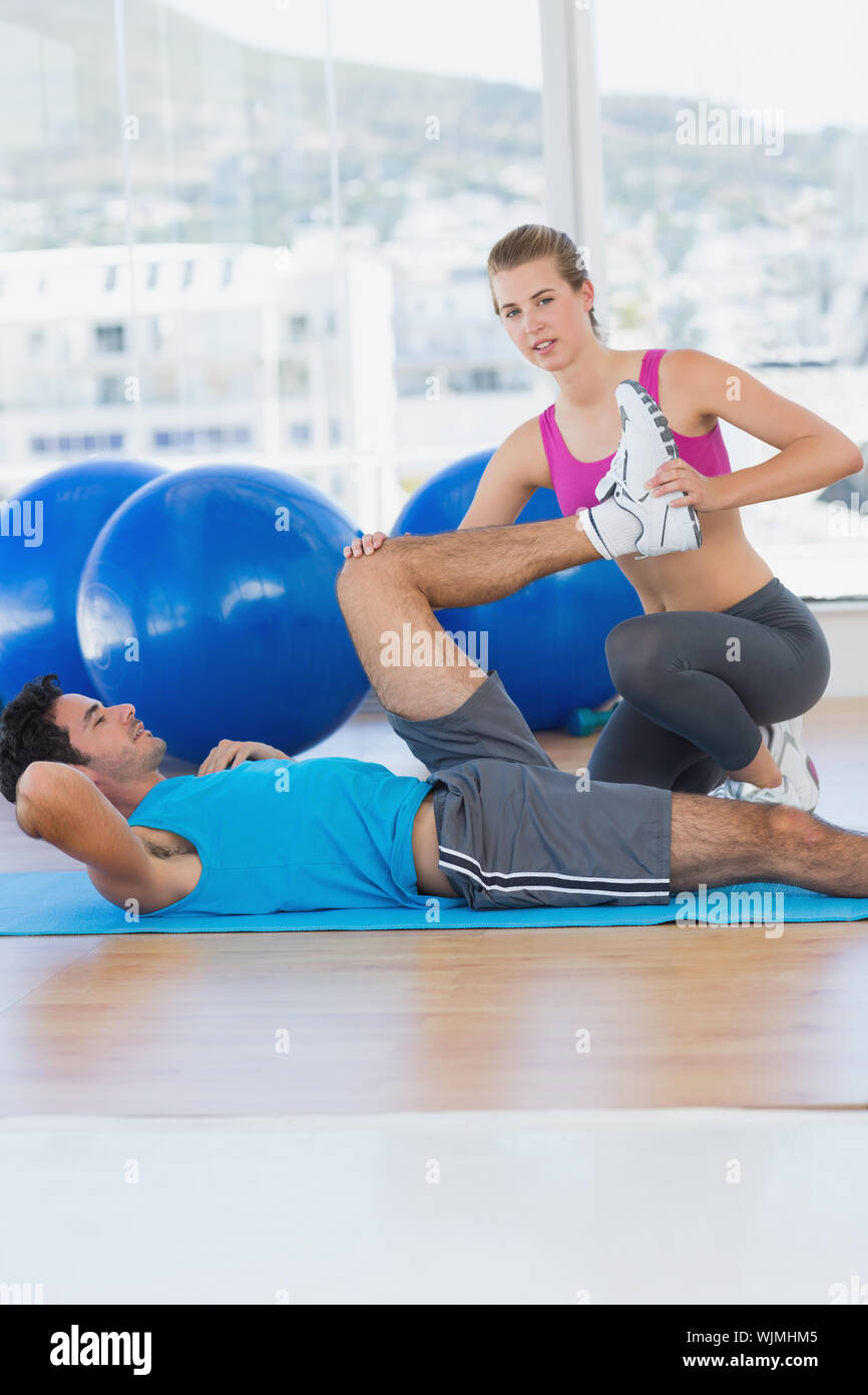 Side view of female trainer helping man with his exercises at a bright ...
