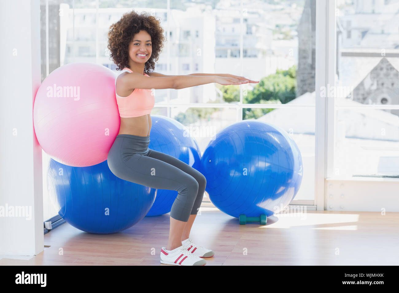 Side view of a sporty young woman with exercise ball in the fitness ...