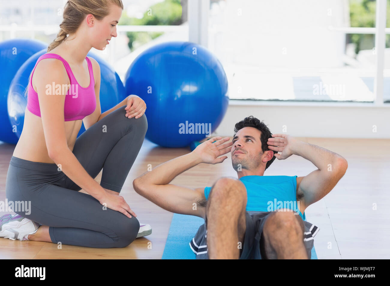 Side view of female trainer helping man with his exercises at a bright ...