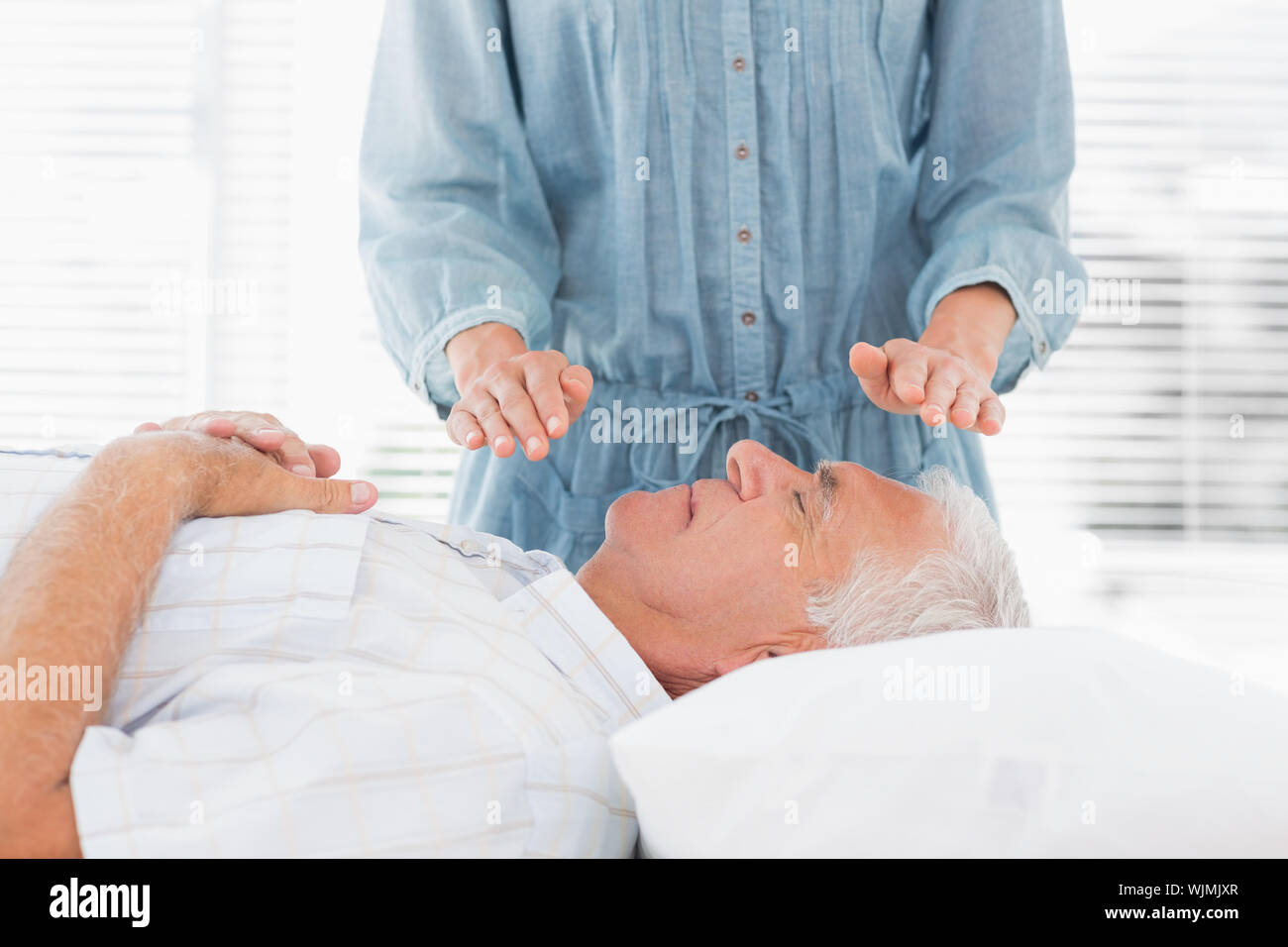 Female therapist performing Reiki over senior man at health spa Stock ...