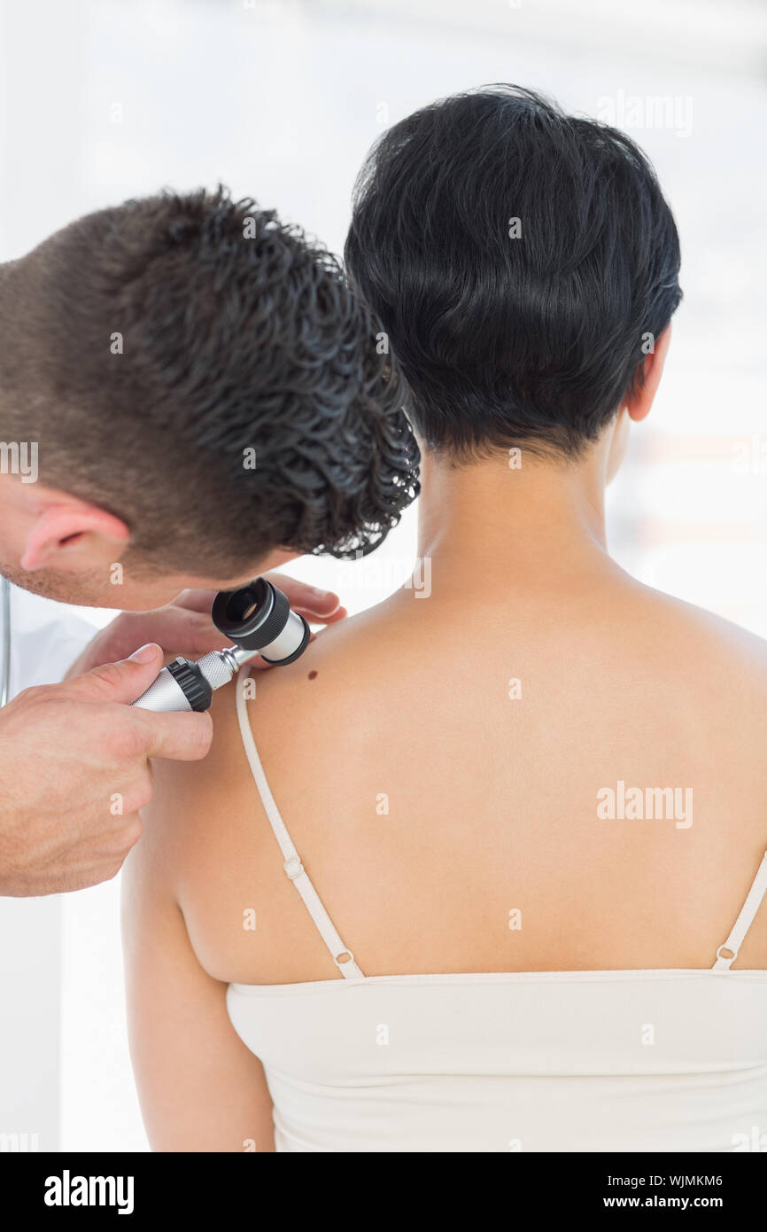 Male dermatologist examining mole on back of woman in clinic Stock ...