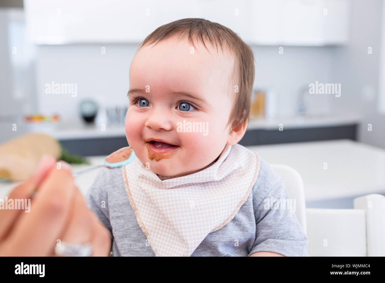 Happy baby boy being fed by mother in kitchen Stock Photo - Alamy