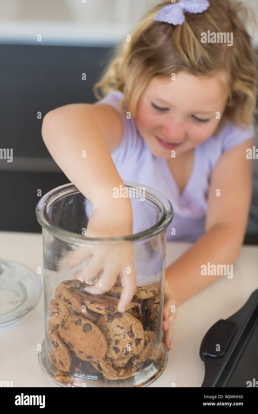 Little girl reaching for cookies in jar at kitchen counter Stock Photo ...