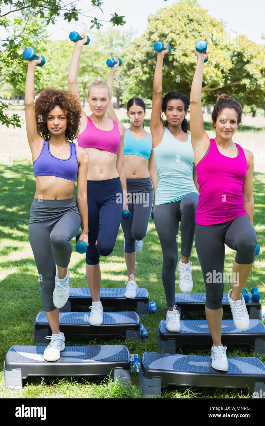 Full length portrait of determined women doing step aerobics with ...